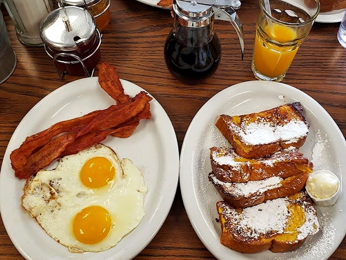 Sunny-side up perfection meets crispy bacon alongside French toast dusted with powdered sugar – breakfast's greatest hits on a single plate.