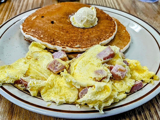 Breakfast perfection doesn't need fancy plating. Ham and eggs alongside golden pancakes with a dollop of butter—simple mathematics that always equals satisfaction.