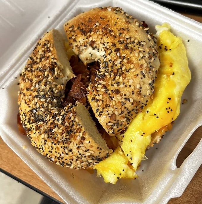 The everything bagel sandwich—where seeds, eggs, and meat perform a breakfast ballet so perfect you'll forget you're eating from a takeout container.