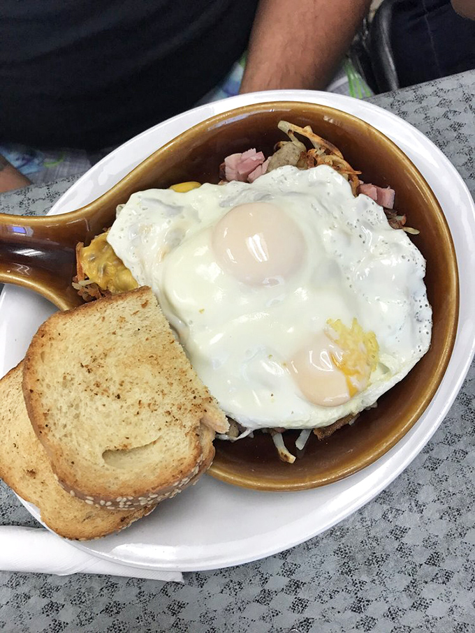 Breakfast perfection in a skillet – sunny eggs crowning a kingdom of potatoes, ham, and cheese. The toast stands ready for yolk-dipping duty.