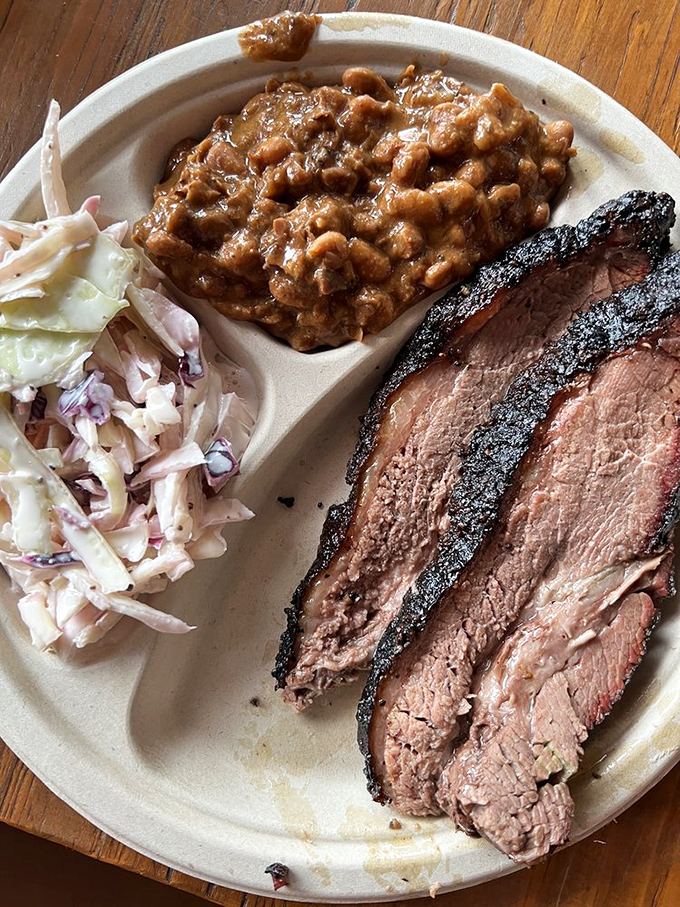 Behold the holy trinity of barbecue perfection: brisket with that coveted smoke ring, creamy beans, and fresh slaw. A plate that speaks fluent Texan with a Pennsylvania accent.