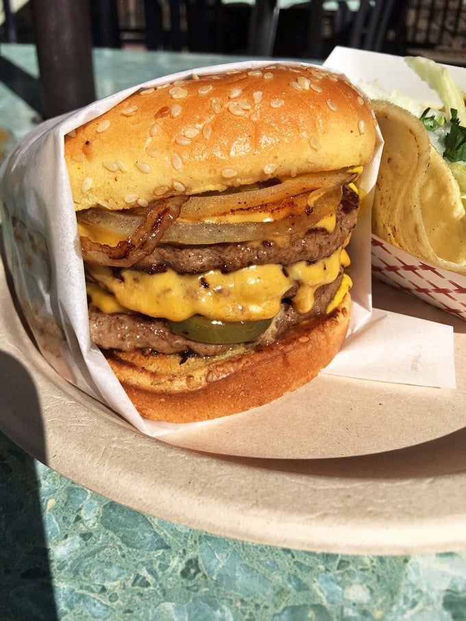 Behold the double cheeseburger in its natural habitat—melty American cheese cascading down perfectly grilled patties like a yellow waterfall.