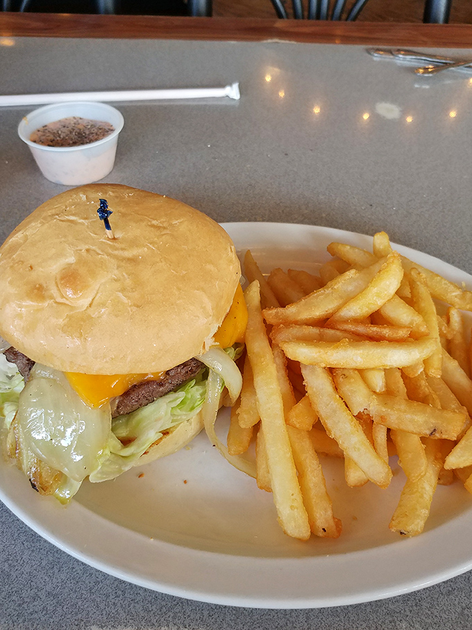 Behold the legendary cheeseburger that locals whisper about – perfectly melted cheese cascading over a juicy patty with golden fries.