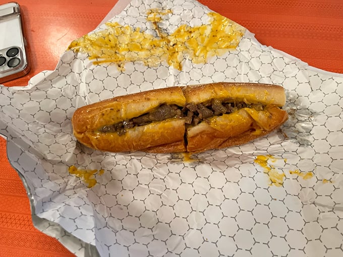 Behold the star of the show – a perfect Philly cheesesteak with golden cheese oozing over thinly sliced ribeye, nestled in that iconic Amoroso roll.