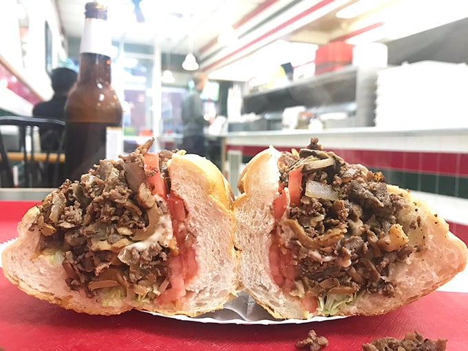 Behold the mighty cheesesteak sandwich, cut in half to reveal its glorious innards. Seasoned meat, fresh veggies, and that perfect bread—a Pennsylvania classic done right.