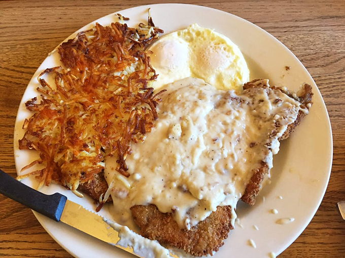 This chicken fried steak doesn't just come with gravy—it's having a passionate love affair with it, while those crispy hash browns stand by as willing accomplices.