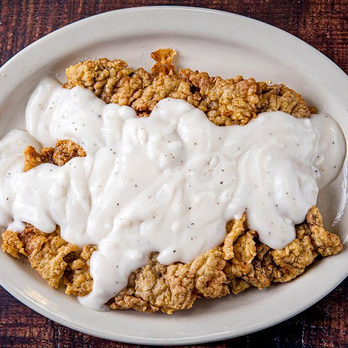 This chicken fried steak isn't just dinner—it's a crispy, golden landscape drowning in creamy gravy that would make your grandmother weep with joy.