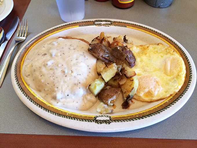 Breakfast nirvana: eggs sunny-side up, potatoes with perfect crispy edges, and that gravy—oh that gravy—blanketing everything in peppery bliss.