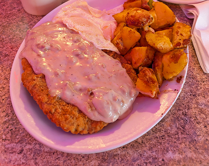 Country-fried steak smothered in creamy gravy alongside golden home fries—comfort food that hugs your soul before it fills your stomach.