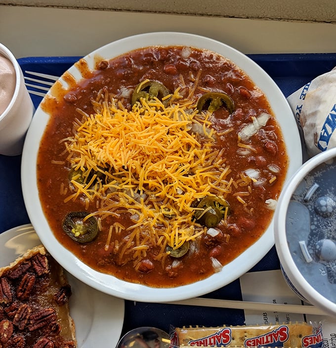 Behold the famous chili in all its glory – a harmonious blend of savory, spicy goodness topped with a sunshine-yellow crown of shredded cheese.