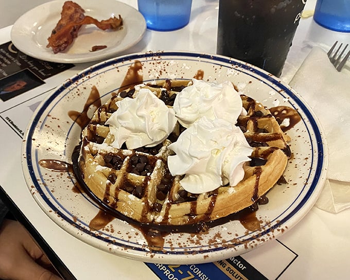 This chocolate waffle isn't just breakfast – it's dessert with an alibi. Whipped cream mountains melt into chocolate rivers, creating morning magic worth setting an alarm for.