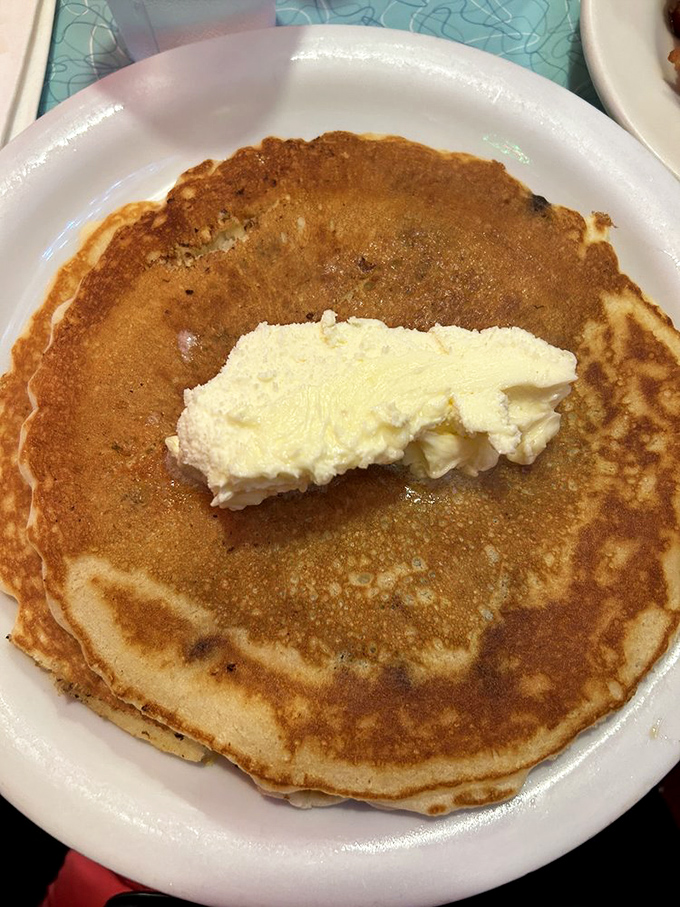 Golden perfection on a plate! This pancake achieves that mythical balance—crispy edges giving way to cloud-like centers, topped with a generous pat of melting butter.