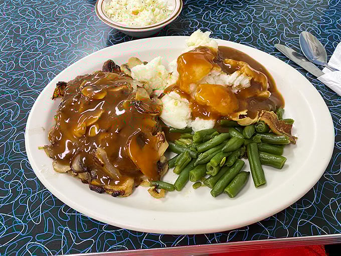 Behold the star attraction: chopped sirloin smothered in rich brown gravy alongside fluffy mashed potatoes and green beans. This isn't just dinner—it's edible nostalgia.