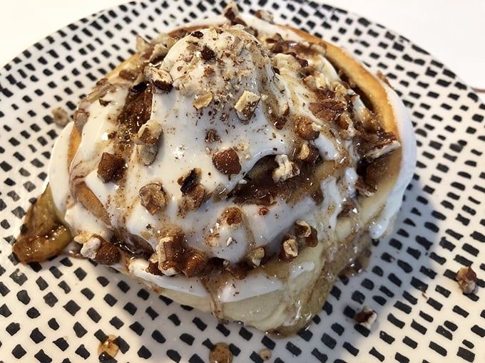This isn't just any cinnamon roll—it's a pillowy spiral of perfection topped with nuts and a drizzle that'll make you weak in the knees.