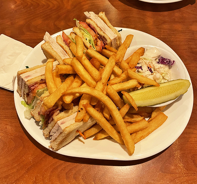This isn't just a club sandwich; it's a skyscraper of comfort with enough fries to make you question whether potatoes are actually vegetables.