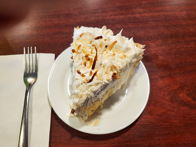Behold the star attraction: coconut cream pie that would make your grandmother simultaneously proud and jealous. That toasted coconut topping isn't decoration—it's a crown.