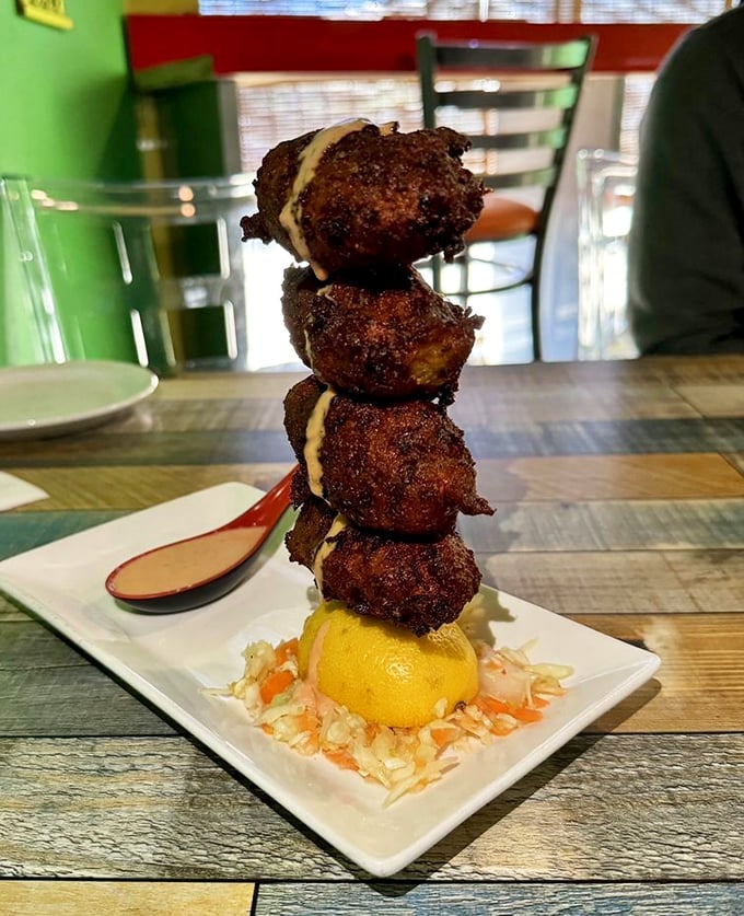 These conch fritters aren't just stacked—they're towering achievements of crispy-outside, tender-inside perfection. That sauce? Liquid sunshine with attitude.