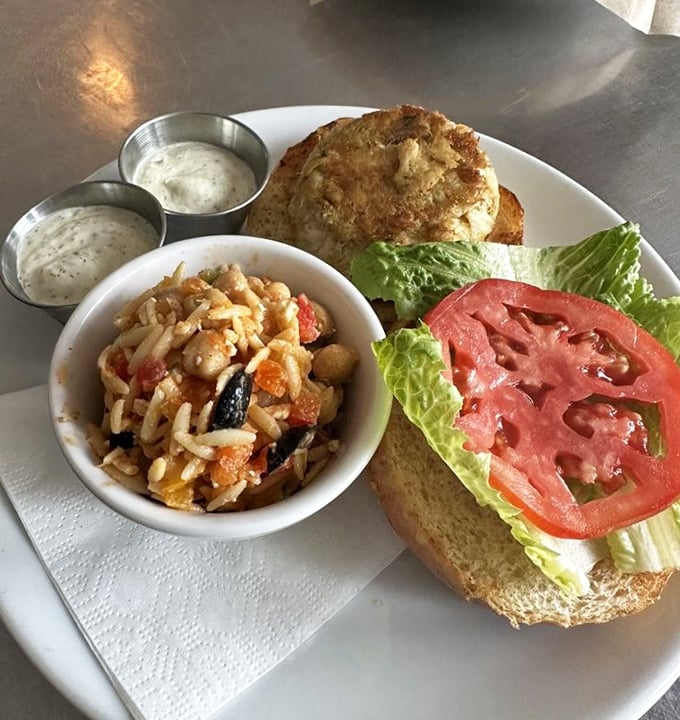 A crab cake sandwich that doesn't hide behind fillers—just pure, sweet crabmeat on a brioche throne with a side of summer in a bowl.