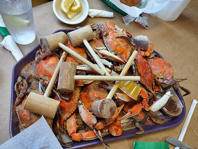 Wooden mallets standing at attention atop a mountain of Old Bay-dusted blue crabs—nature's puzzle boxes filled with sweet rewards for the patient.