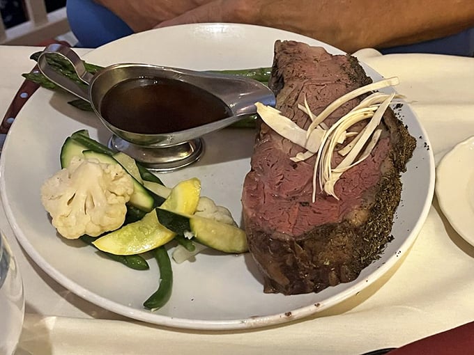 A perfectly cooked prime rib arrives like royalty with its crown of fresh vegetables and a boat of au jus that's practically liquid gold.