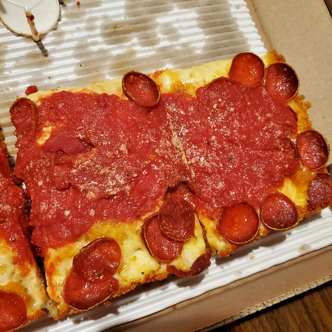 The pepperoni cups forming little flavor pools are not accidents—they're divine intervention. This Detroit-style slice makes round pizza seem like a missed opportunity.