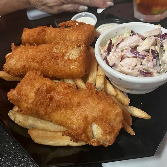 Golden-battered fish that shatters with each bite, alongside crispy fries and creamy slaw—the holy trinity of diner perfection.