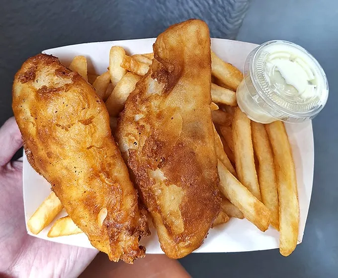 Golden-battered fish that shatters with each bite, nestled alongside perfectly crisp fries. This isn't just fish and chips—it's edible poetry.