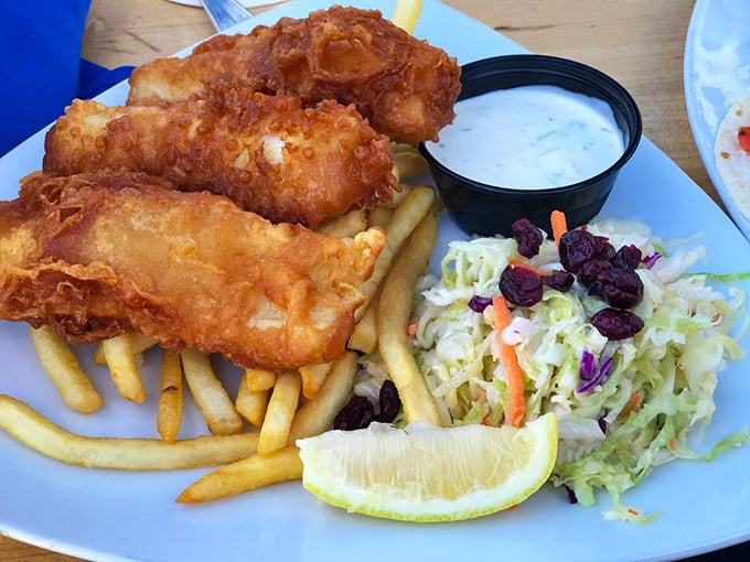 Golden-battered fish that shatters with each bite, alongside crispy fries and tangy slaw – this isn't just fish and chips, it's edible sunshine.