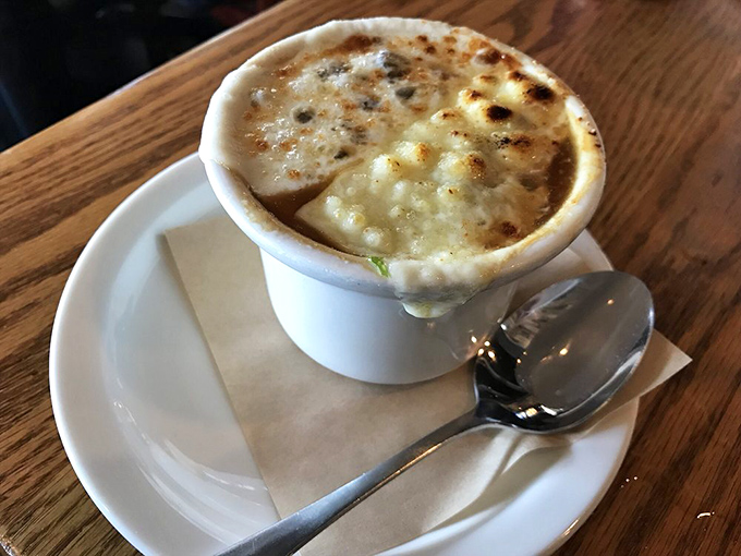 Behold the legendary French onion soup in all its glory—a bubbling cauldron of caramelized perfection beneath a golden cheese canopy that stretches like a dream.