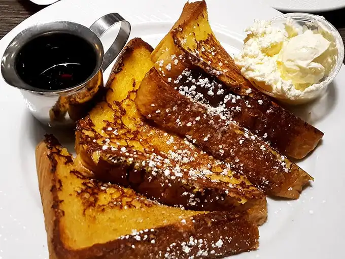 Golden-brown French toast that's achieved celebrity status in Chicago—crisp edges, custardy center, and that perfect dusting of powdered sugar.