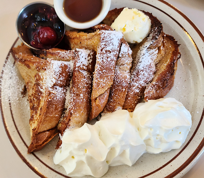 This isn't just French toast—it's a masterclass in breakfast architecture, complete with powdered sugar snowfall and whipped cream mountains.