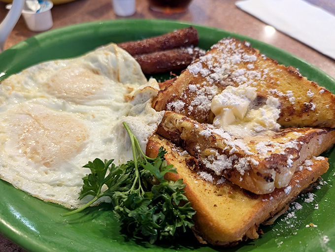 Breakfast nirvana achieved: golden French toast dusted with powdered sugar, eggs cooked just right, and bacon that makes you question all other bacon.