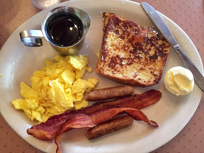 The legendary French toast combo – golden perfection flanked by eggs and bacon like delicious bodyguards protecting breakfast royalty.