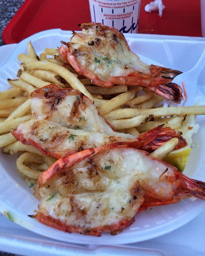 These aren't just shrimp—they're proof that sometimes the best things in life come with tails. Perfectly charred, nestled among golden fries, they're the celebrities of this seafood show.
