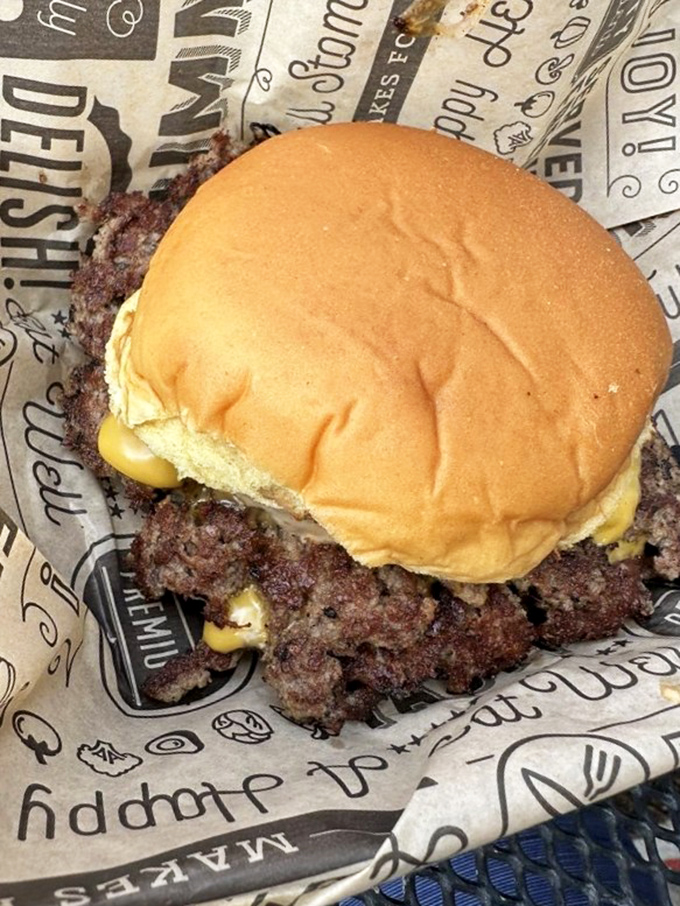 This isn't just a burger—it's edible architecture with crispy-edged beef spilling beyond the bun's borders in delicious rebellion.