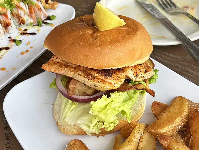 Behold the star of the show—a grouper sandwich that makes other fish sandwiches look like they're not even trying. That lemon wedge isn't garnish, it's essential equipment.
