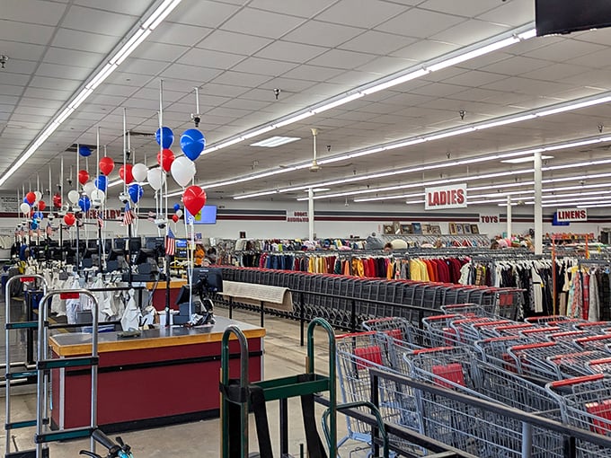 Red, white, and blue balloons dance overhead as shoppers navigate the color-coded clothing aisles—America's favorite pastime isn't baseball, it's bargain hunting.