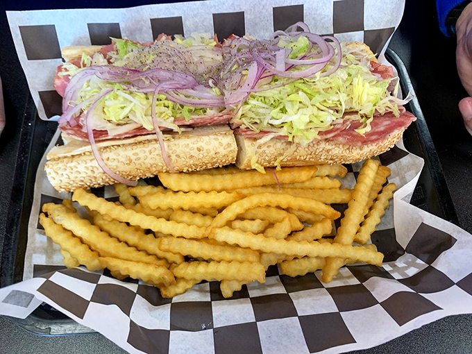 Behold the Italian hoagie in its natural habitat—piled high with meats, dressed with shredded lettuce, and flanked by crinkle-cut sentinels.