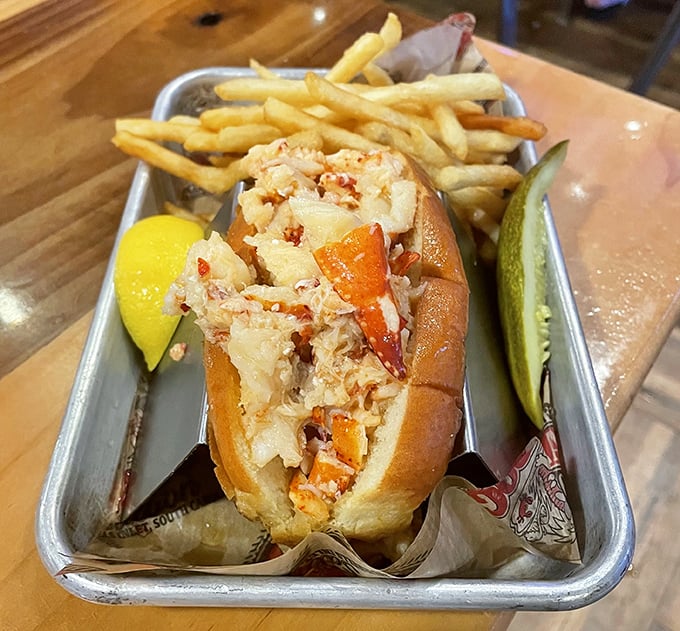 The lobster roll arrives like a celebrity on a metal tray—chunks of sweet meat nestled in a buttery bun with crispy fries standing guard.