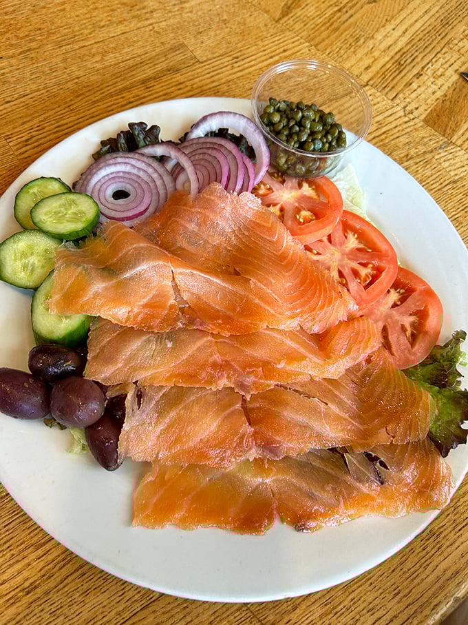 Smoked salmon arranged with artistic precision alongside capers and red onions – proof that simple ingredients handled with respect create culinary magic.
