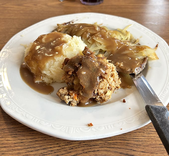 Cloud-like mashed potatoes swimming in savory gravy—proof that sometimes the simplest foods deliver the most profound joy.