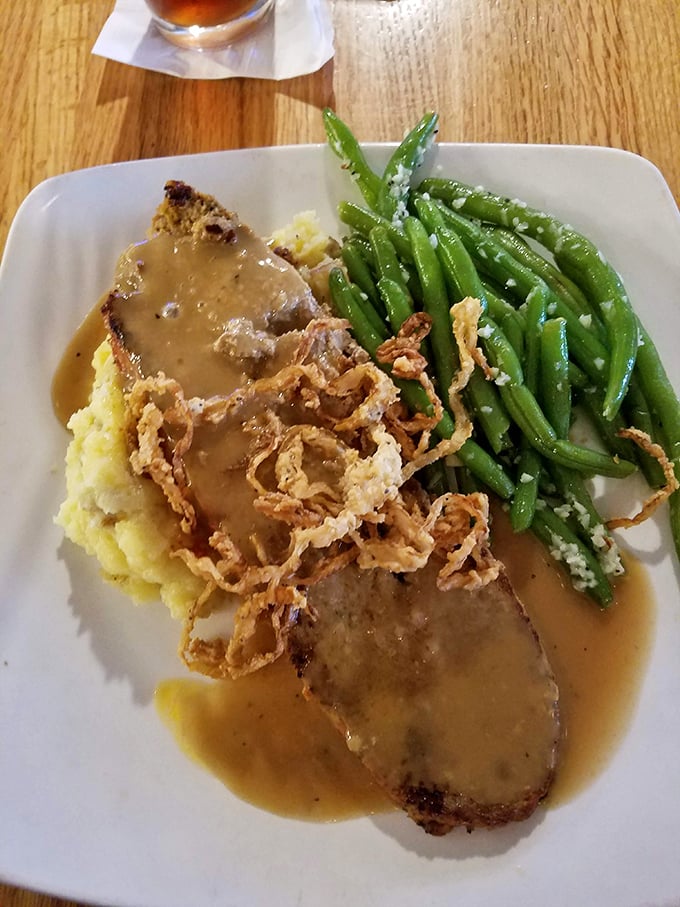 Meatloaf nirvana achieved: tender slices bathed in savory gravy, alongside cloud-like mashed potatoes and green beans that actually taste like vegetables should.
