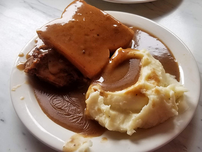 Behold the star attraction: meatloaf swimming in gravy with cloud-like mashed potatoes. This isn't just food—it's a warm hug on a plate. 