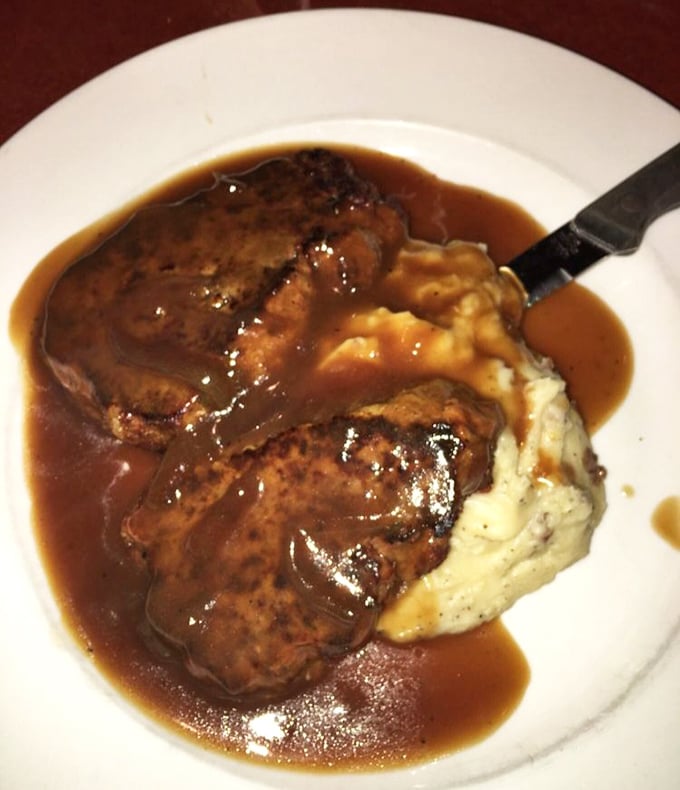 Meatloaf swimming in rich gravy alongside cloud-like mashed potatoes—comfort food that doesn't just hug your soul, it gives it a warm blanket.