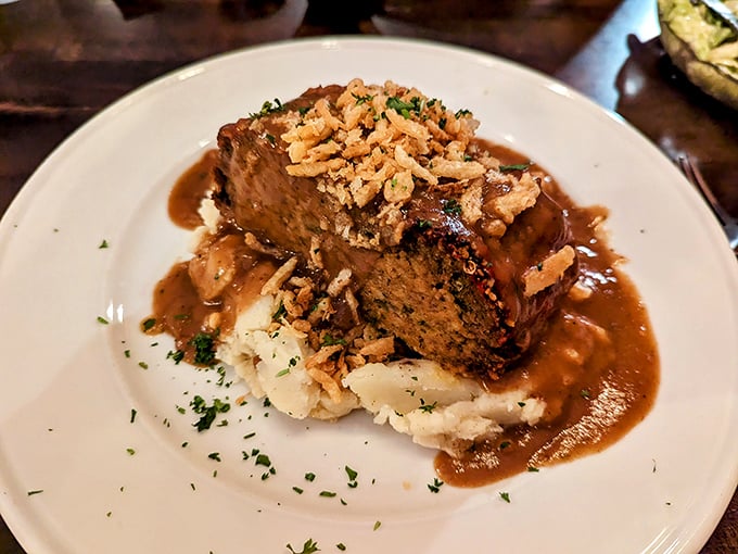 The legendary meatloaf in all its glory—sitting atop cloud-like mashed potatoes, bathed in savory gravy, and topped with crispy onions. Comfort food elevated to an art form.