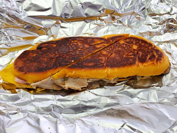 The Media Noche reveals its secrets: layers of succulent meats and cheese pressed between sweet egg bread, all wrapped in that telltale foil of anticipation.
