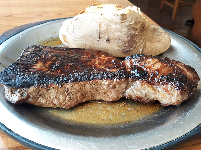 A perfectly seared New York strip that doesn't need fancy garnishes – just a humble baked potato and your undivided attention.