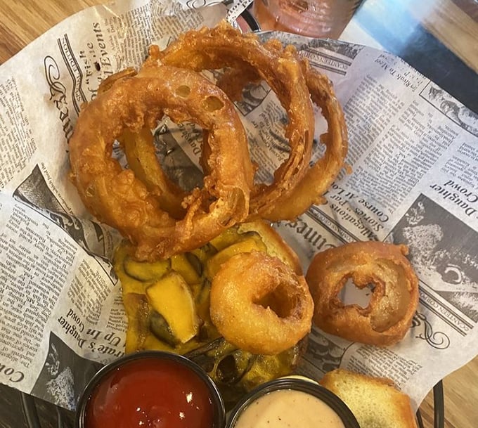 Golden halos of happiness served on newspaper—these aren't just onion rings, they're edible jewelry that somehow improves your day with each crunchy bite.