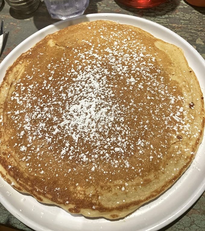 Behold the pancake of your dreams—golden, dusted with powdered sugar, and waiting patiently for its maple syrup baptism.