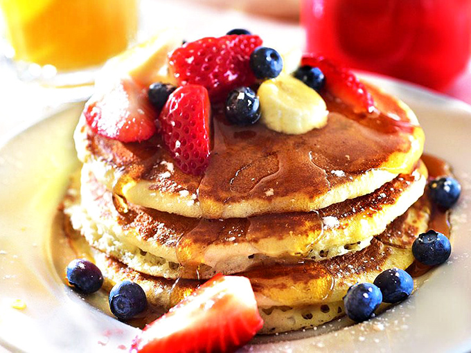 These pancakes aren't just breakfast, they're an event – golden stacks adorned with berries that pop like edible jewels in morning sunlight.